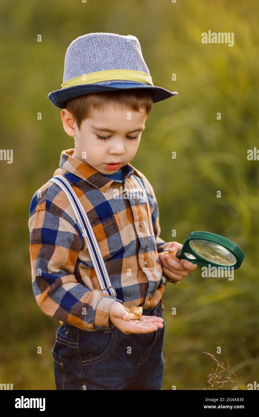 little boy exploring nature in the meadow with a magnifying glass Stock ...