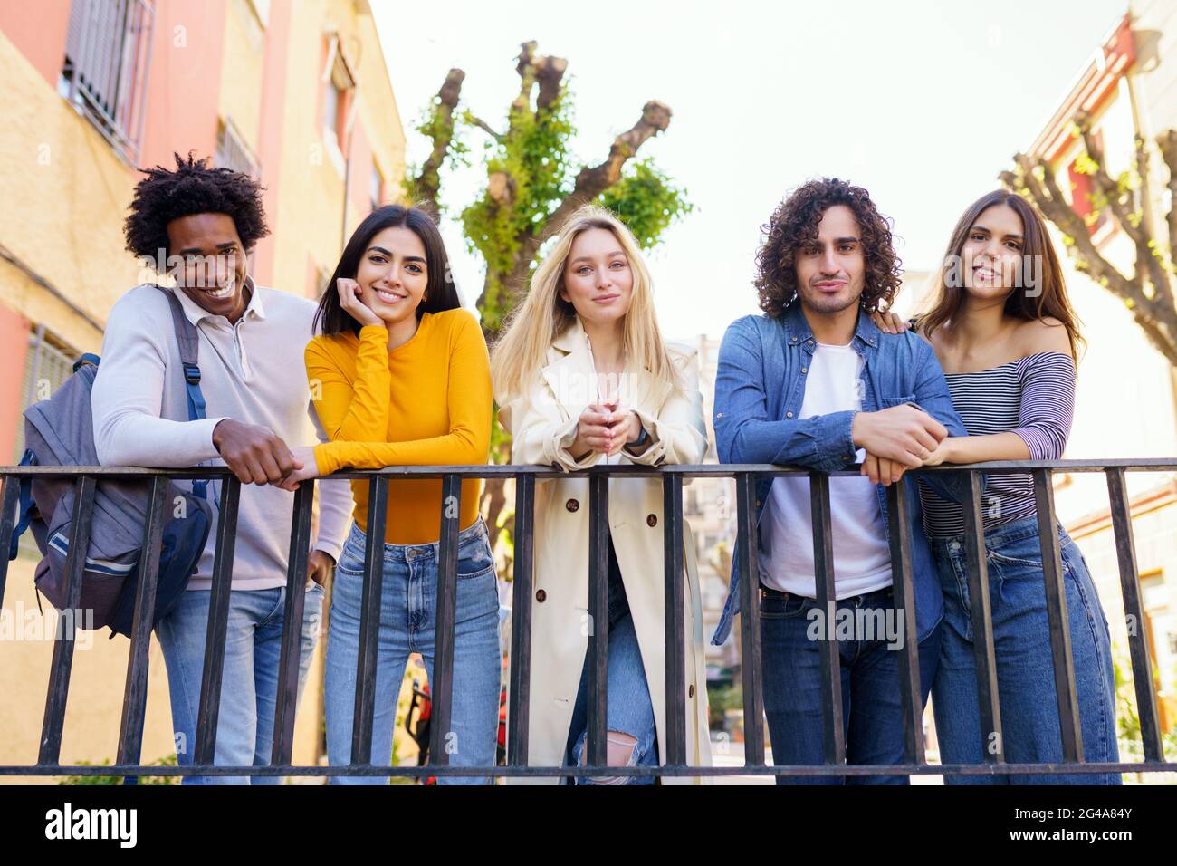 Multi-ethnic group of friends gathered in the street leaning on a ...