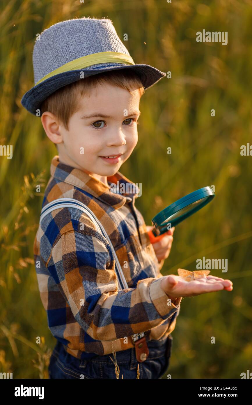 little boy exploring nature in the meadow with a magnifying glass Stock ...