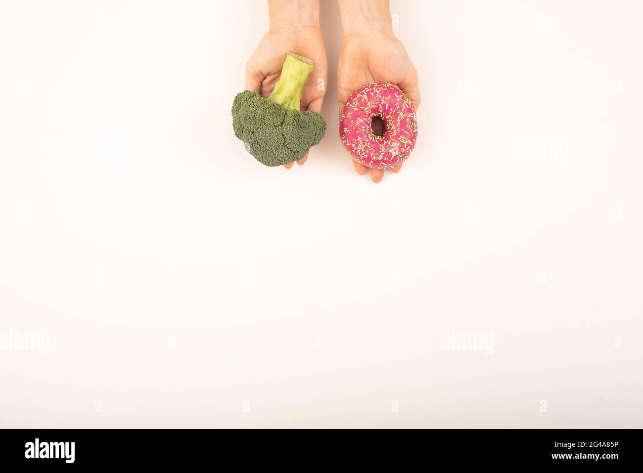 Comparison of eating habits. Woman holding broccoli and donut on a ...