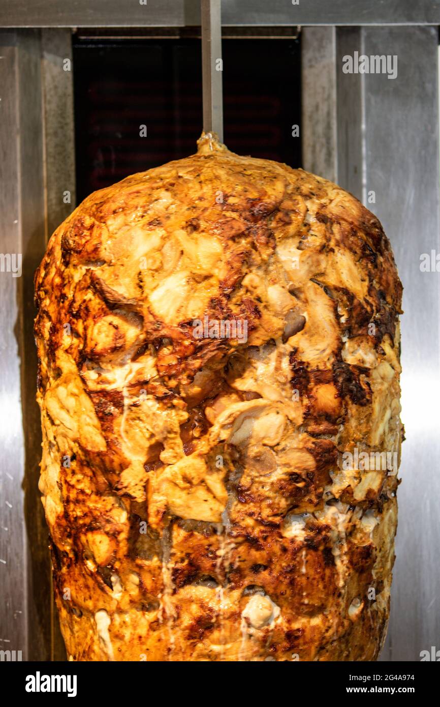 A closeup of a vertical rotisserie roasting appetizing meat for ...