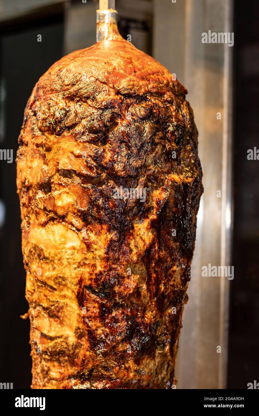 A closeup of a vertical rotisserie roasting appetizing meat for ...