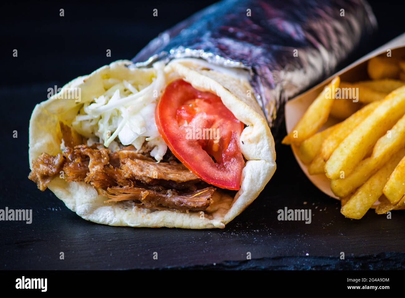 A closeup of appetizing shawarma stuffed with meat, tomato, and sauce ...