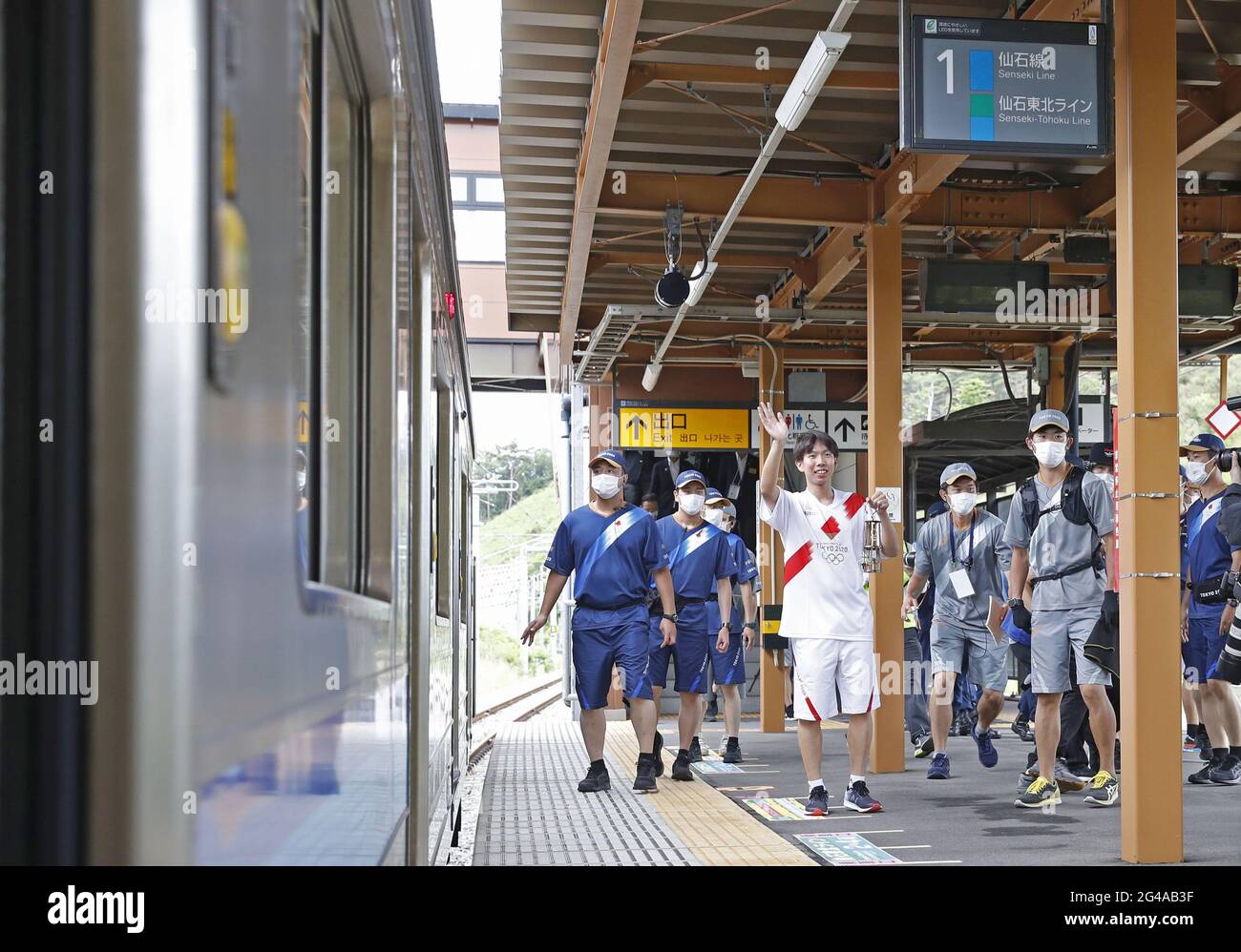 A Tokyo Olympic torch relay participant carrying the Olympic flame in a ...