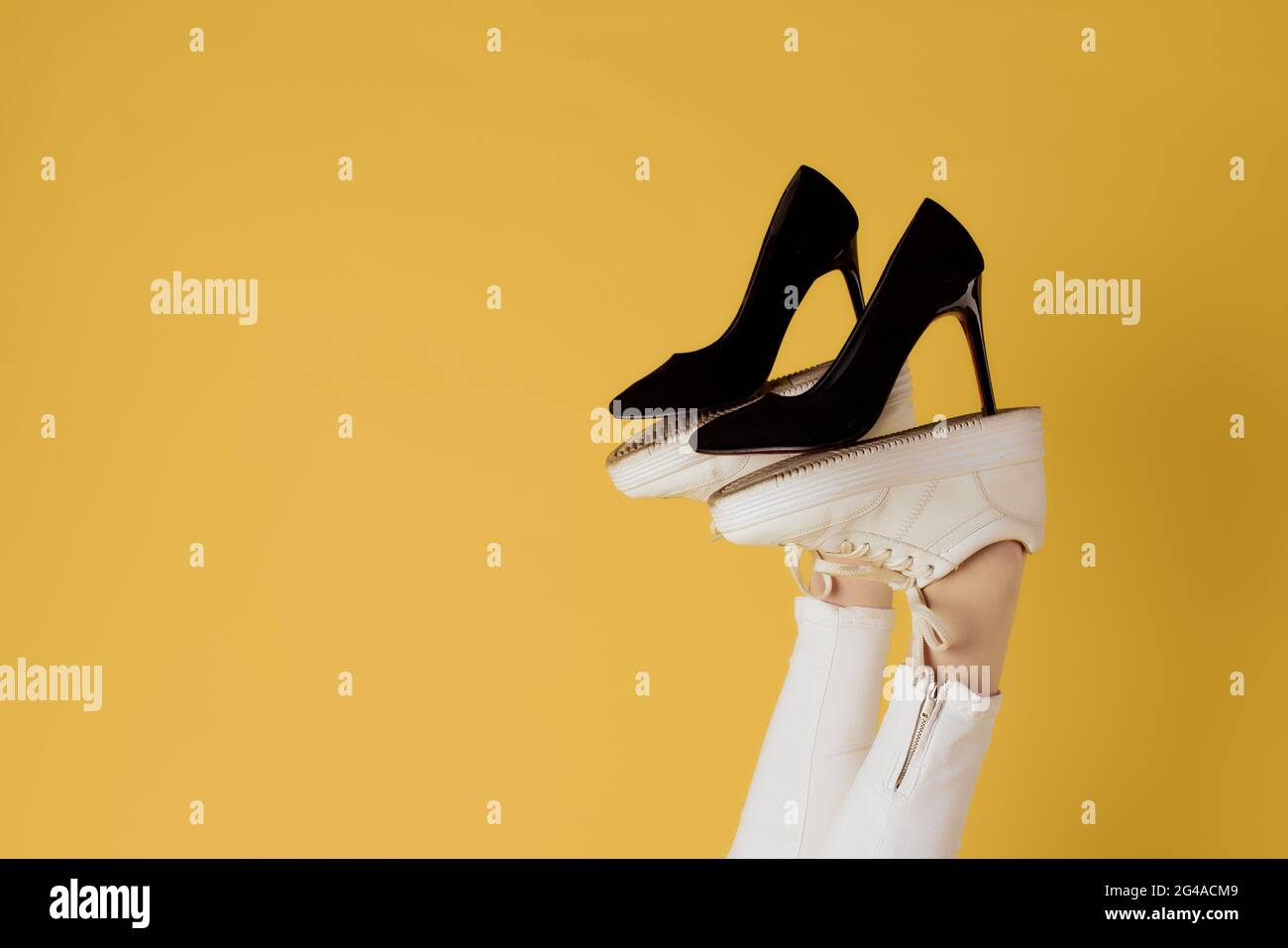 womens black shoes on inverted legs yellow background Stock Photo - Alamy