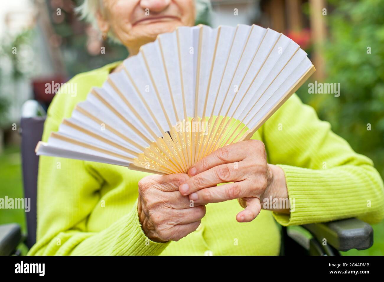 Senior woman holding waving fan on a hot summer day Stock Photo - Alamy