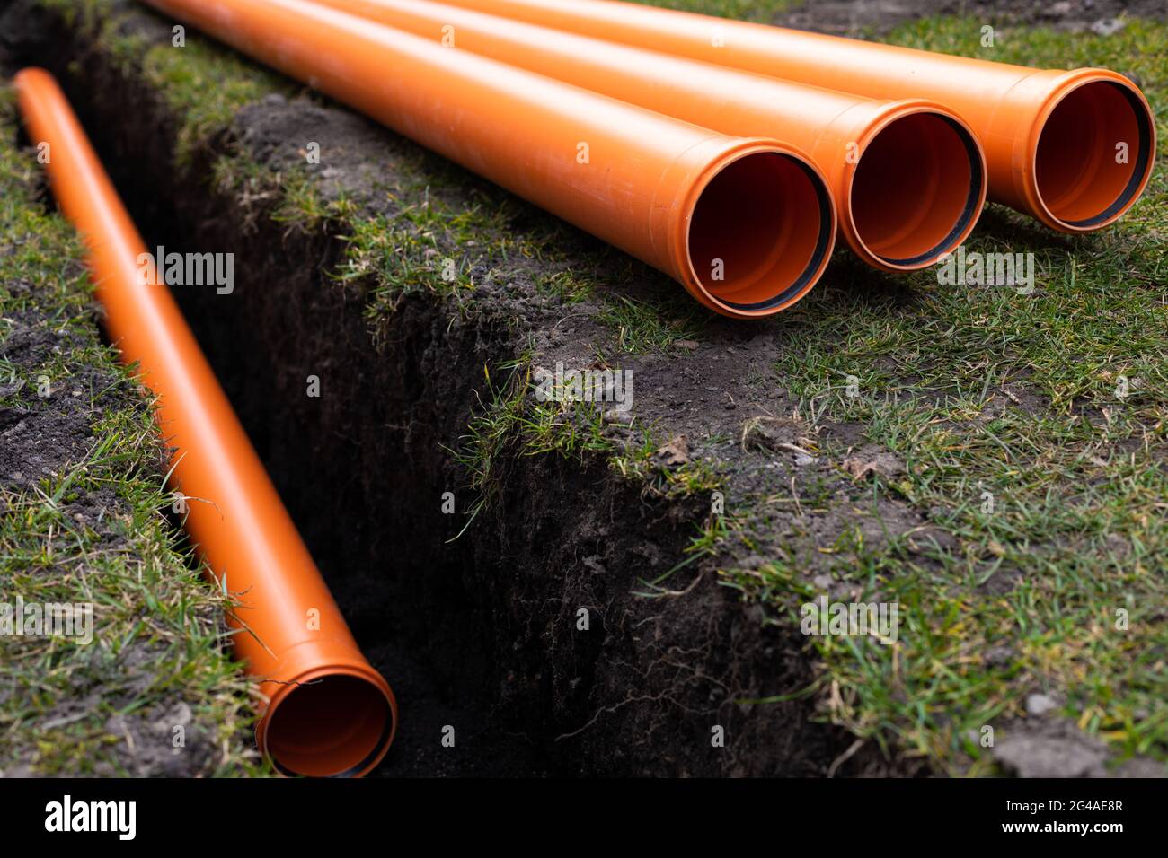 Laying down orange PVC drainage pipes into the ground Stock Photo - Alamy