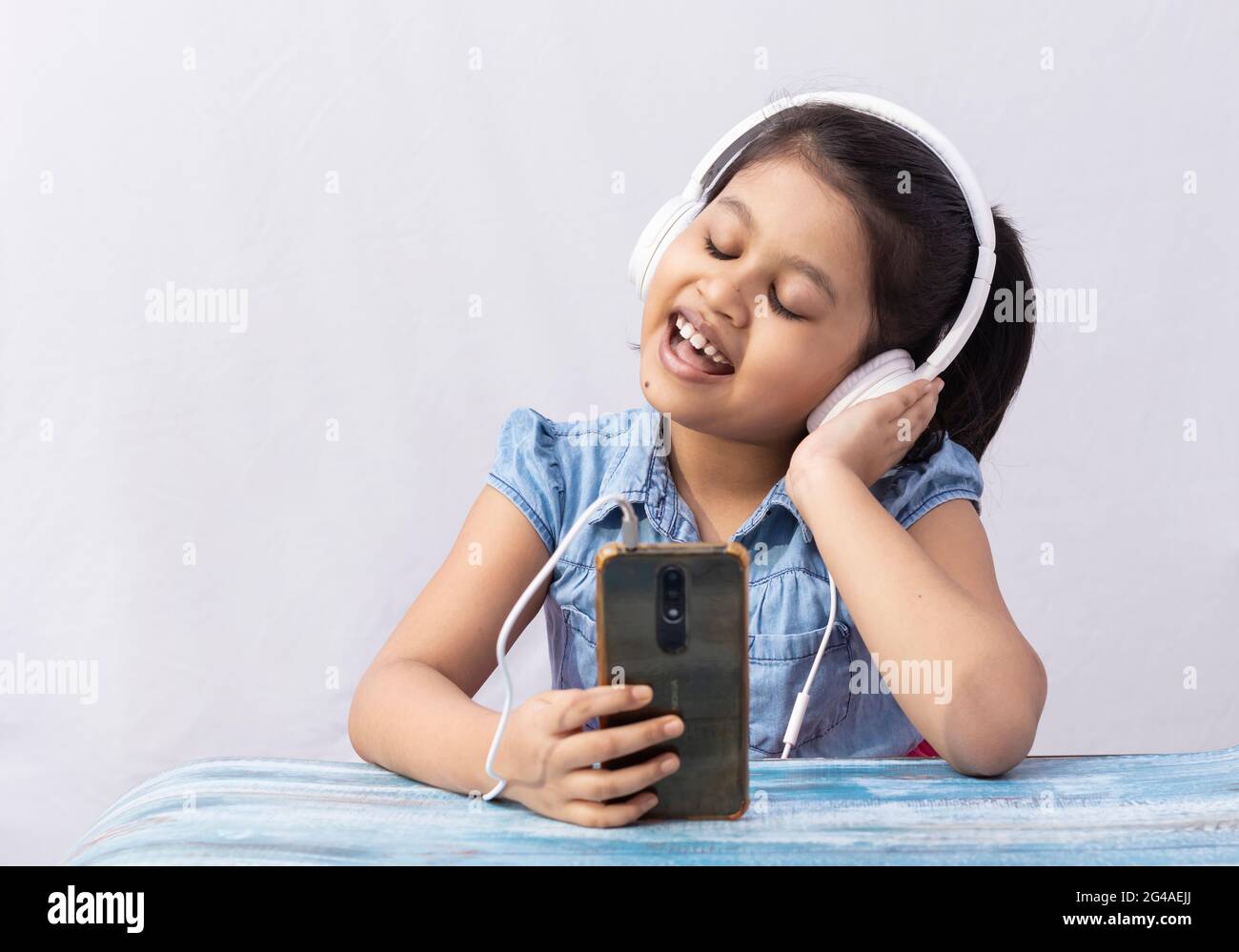 A cute Indian girl child listening to music with eyes closed and ...