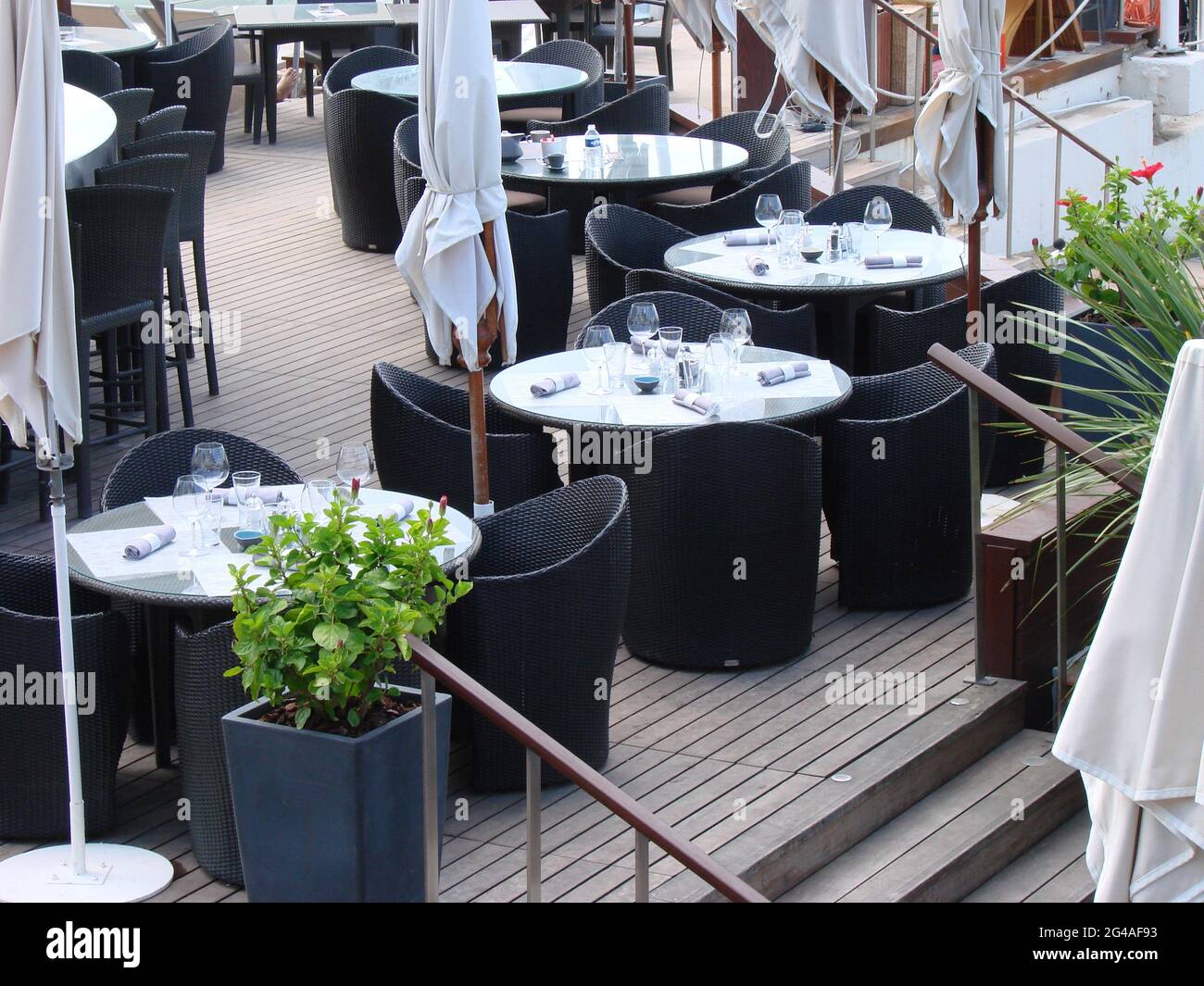 A high angle shot of an outdoor cafe with set round tables and closed ...