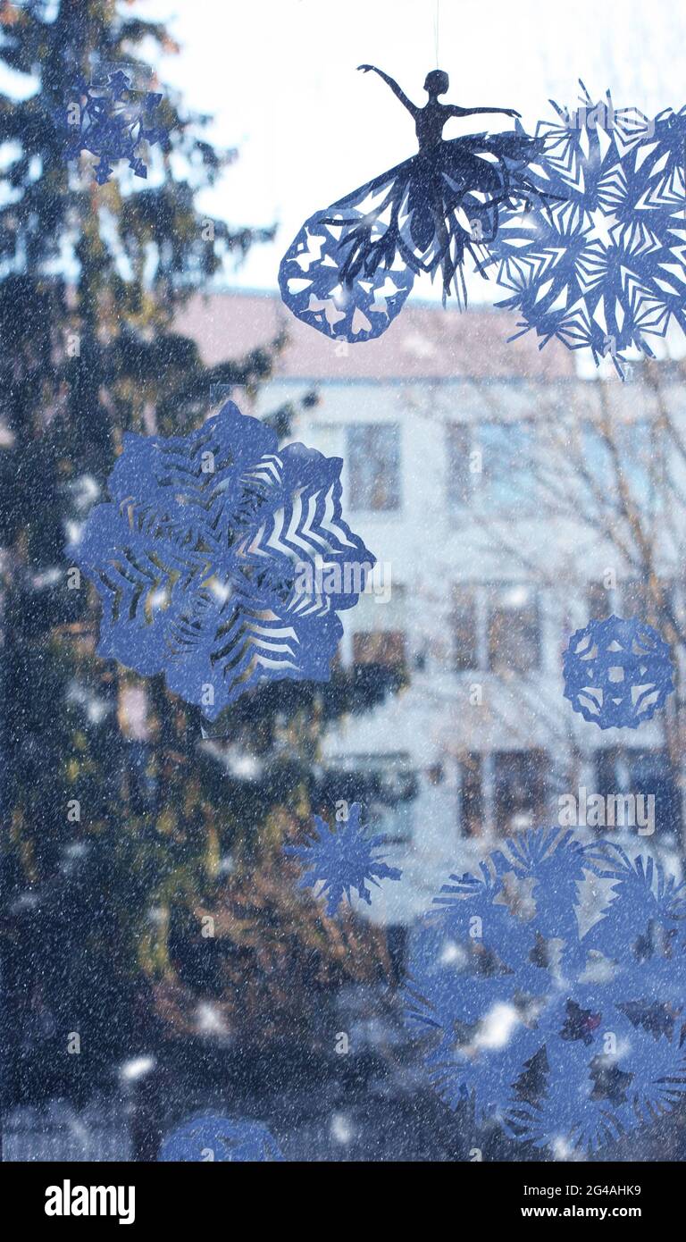 Paper snowflake and ballerina on the window glass on snowfall ...