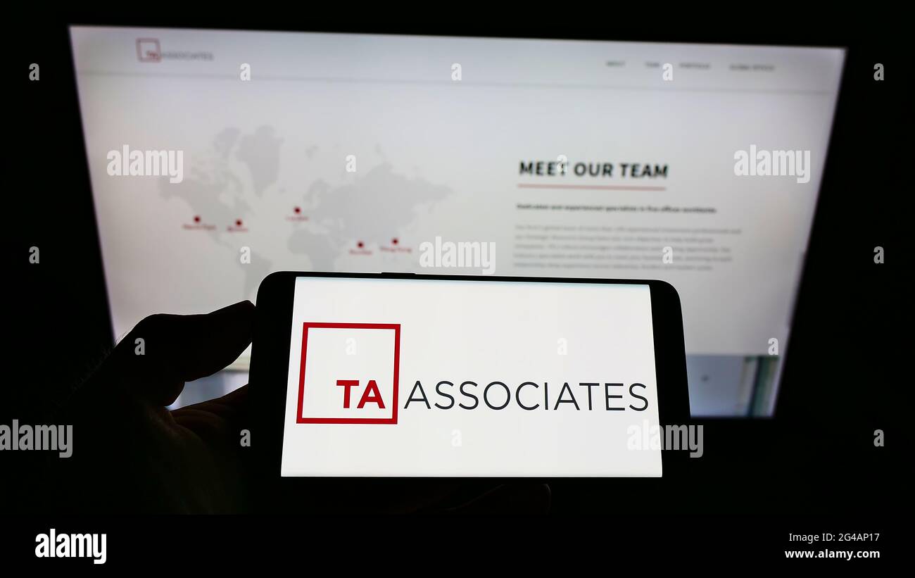 Person holding smartphone with logo of US private equity firm TA ...