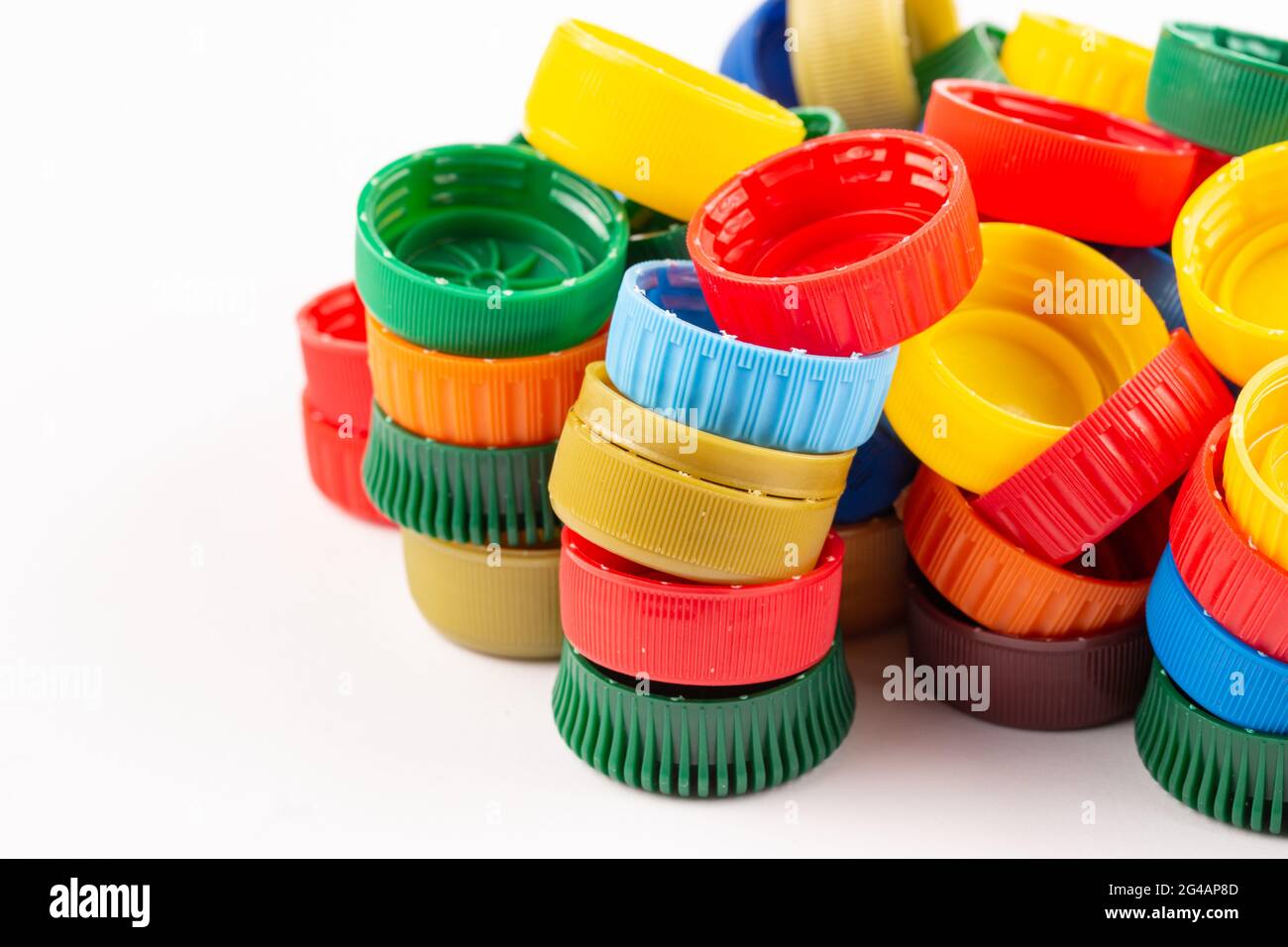 Many multi-colored plastic bottle caps on a white background. Recycling ...