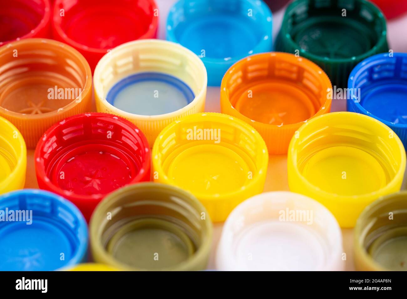 Many multi-colored plastic bottle caps on a white background. Recycling ...