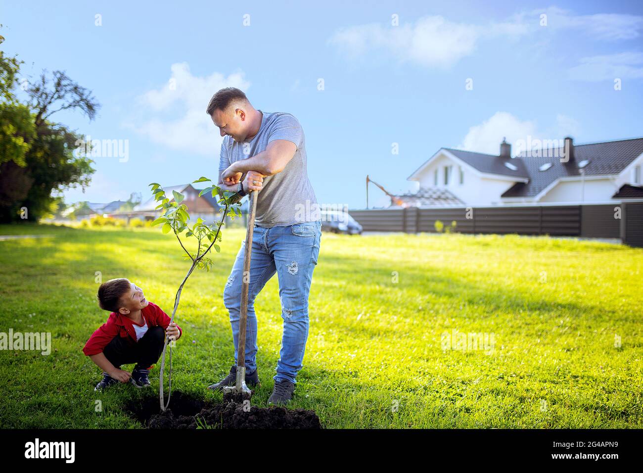 side view father looking how son planting tree with shovel at front of ...