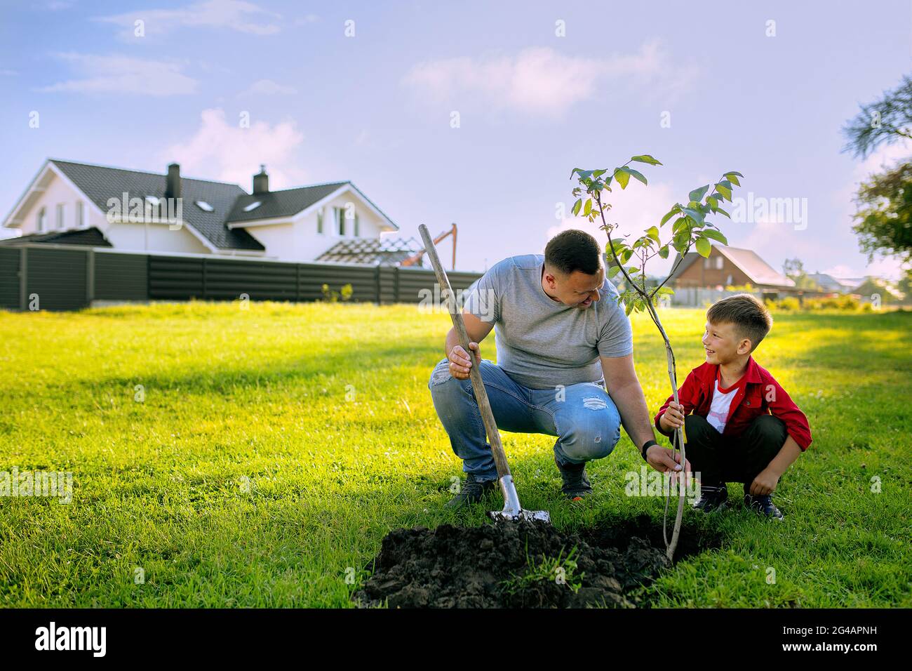 side view father looking how son planting tree with shovel at front of ...