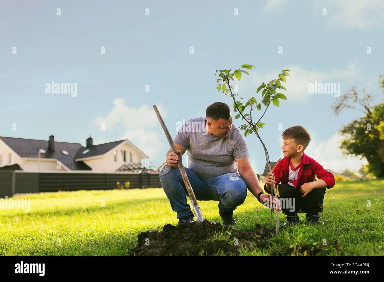 side view father looking how son planting tree with shovel at front of ...