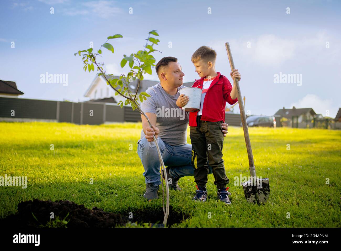 side view father looking how son planting tree with shovel at front of ...
