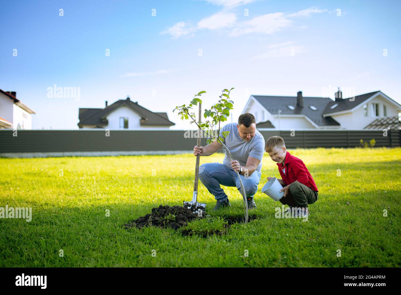side view father looking how son planting tree with shovel at front of ...