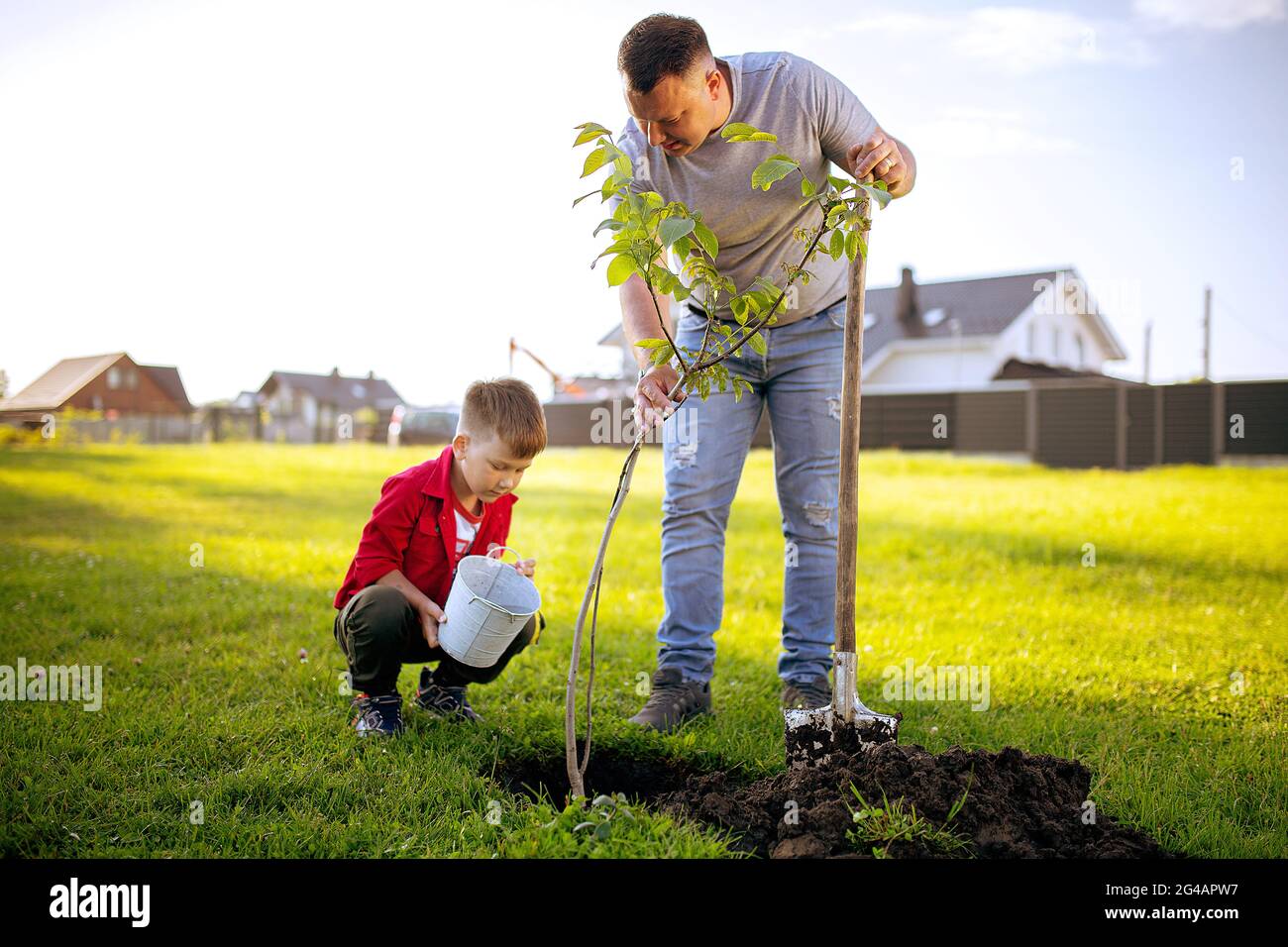 side view father looking how son planting tree with shovel at front of ...