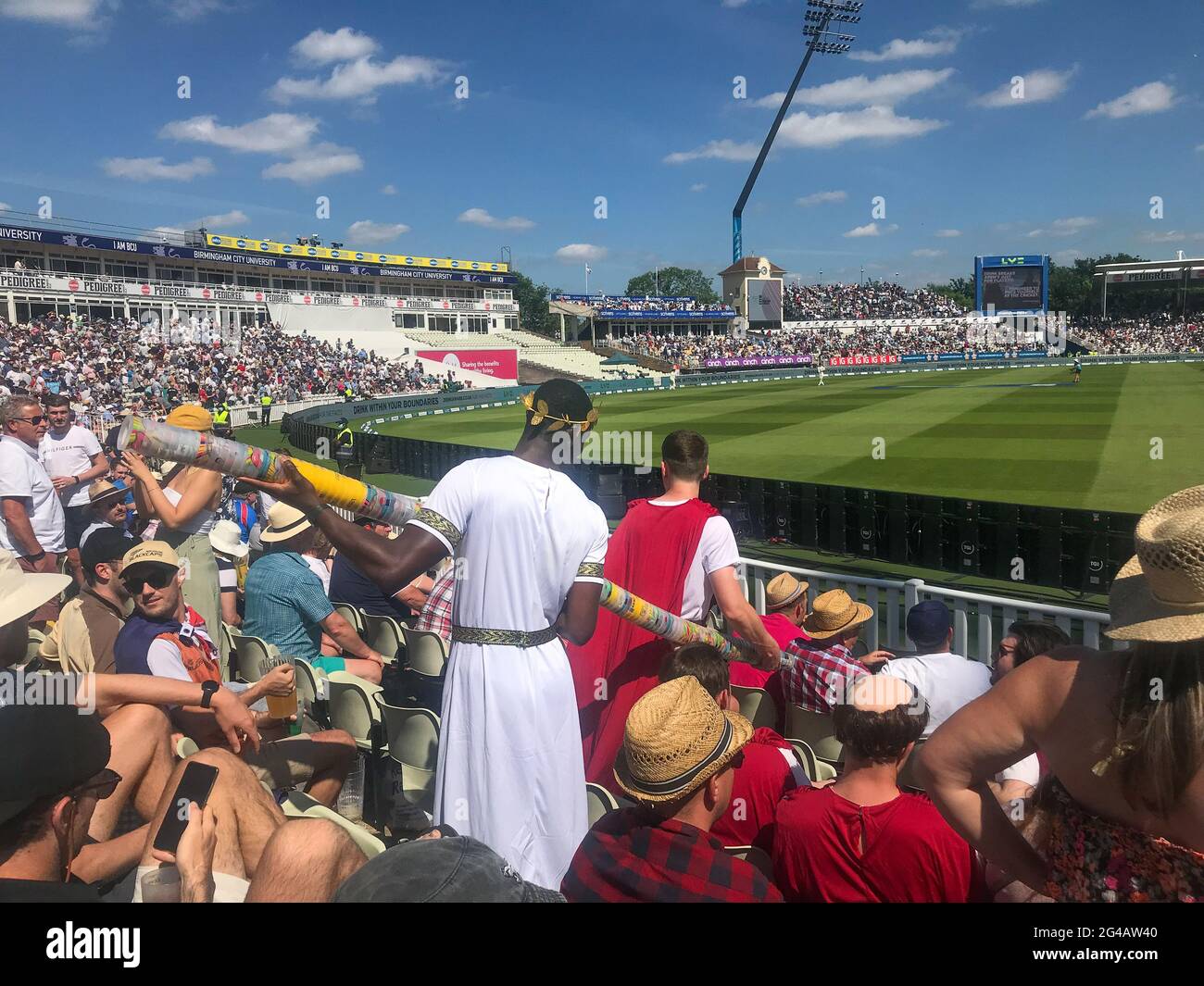 Crowds having fun at a cricket match constructing a plastic beer snake ...