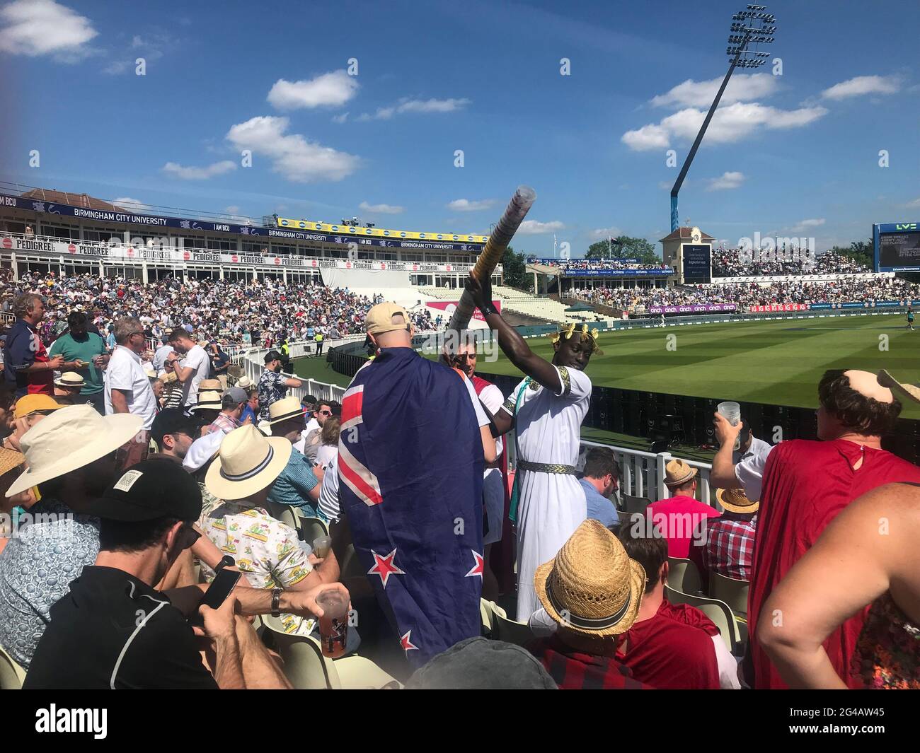 Crowds having fun at a cricket match constructing a plastic beer snake ...