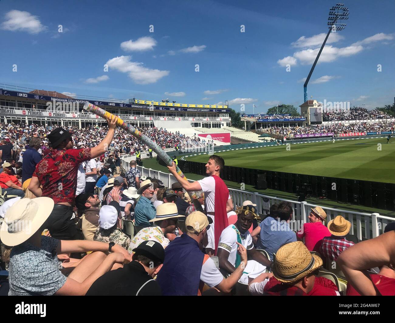 Crowds having fun at a cricket match constructing a plastic beer snake ...