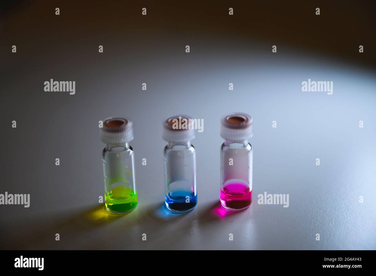 Three colourful solution in different LCMS glass vial on a white bench ...