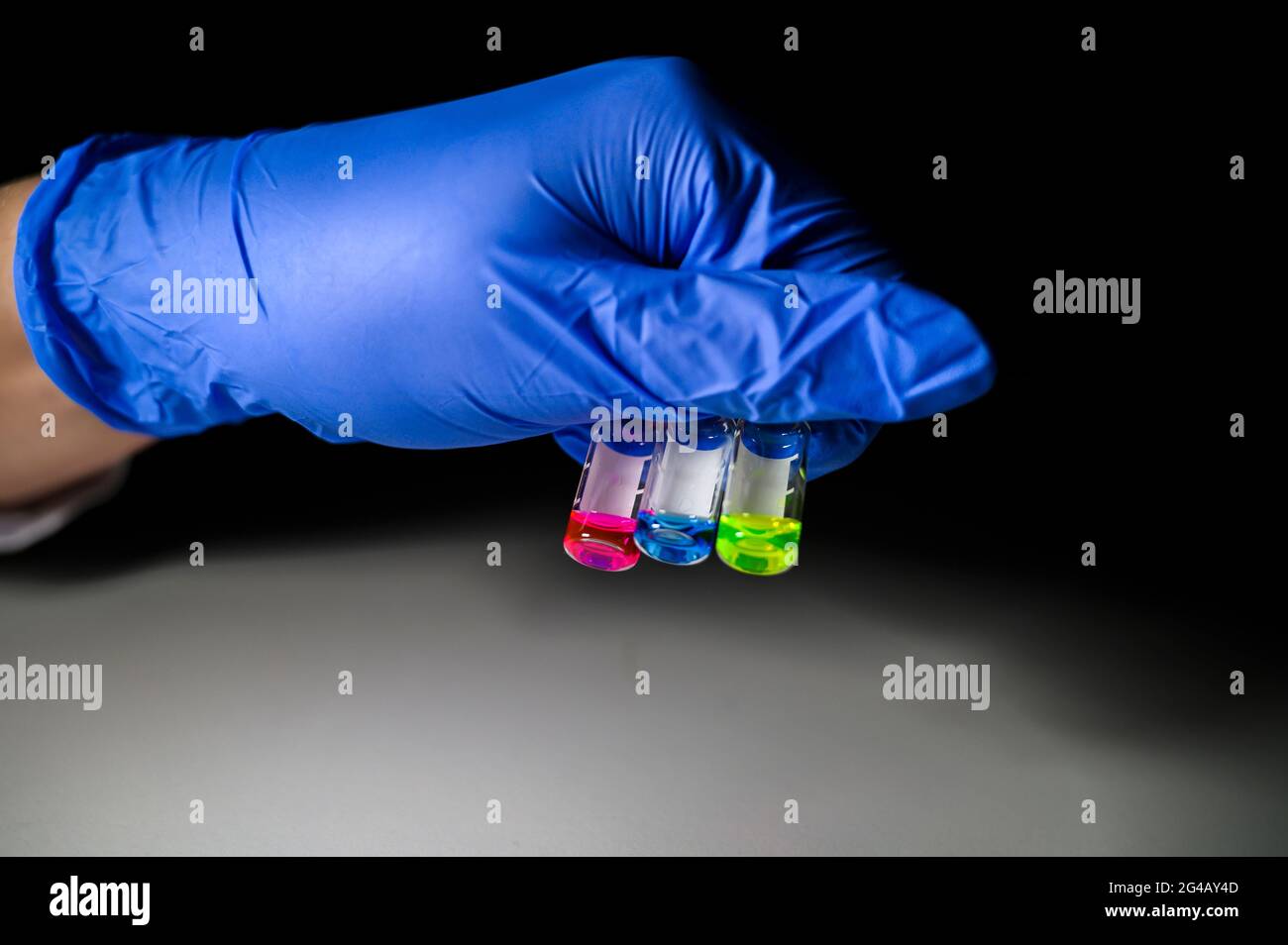 Scientist holding three colourful solution in different LCMS glass vial ...