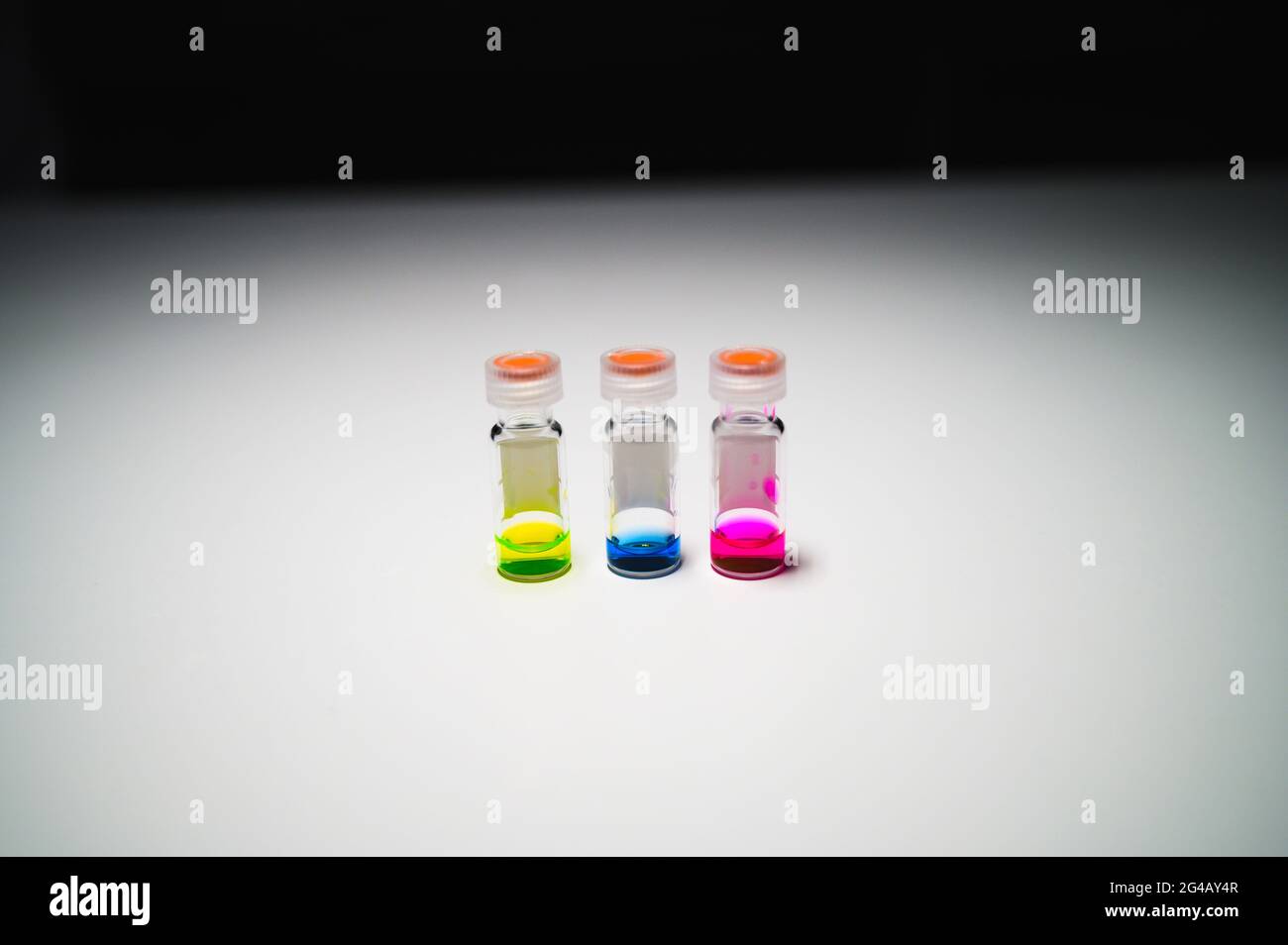Three colourful liquid in different LCMS glass vial on a white bench ...