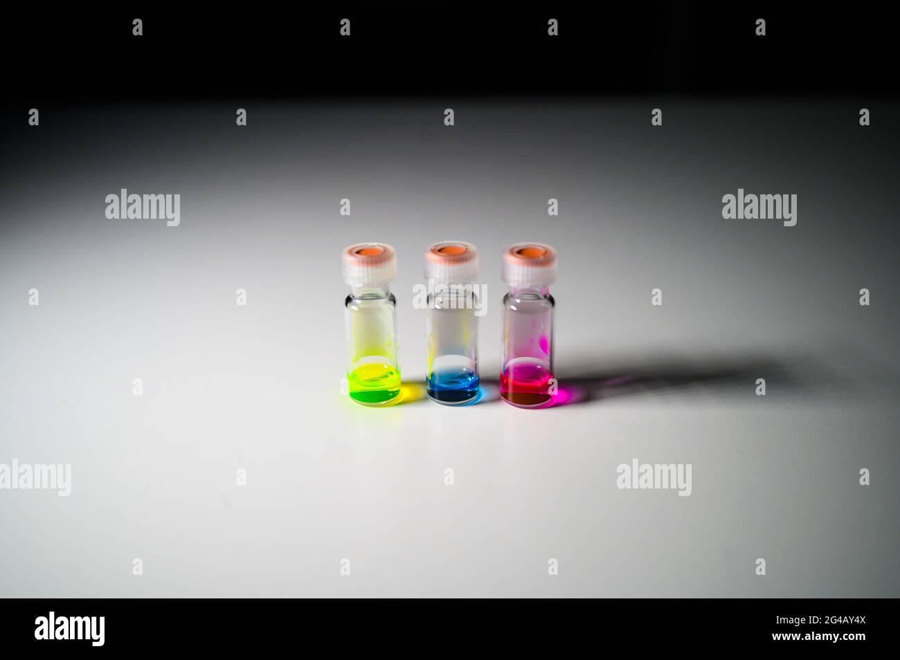 Three colourful solution in different LCMS glass vial on a white bench ...
