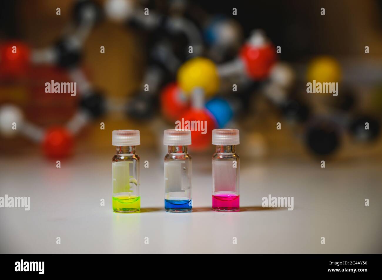 Three colourful solution in different glass vial on a white bench ...