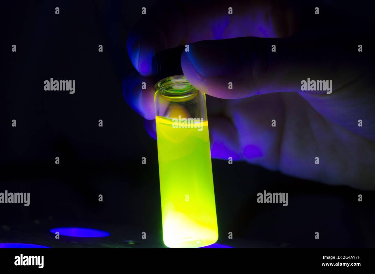 Researcher hand holding yellow close up photochemical reaction in glass ...