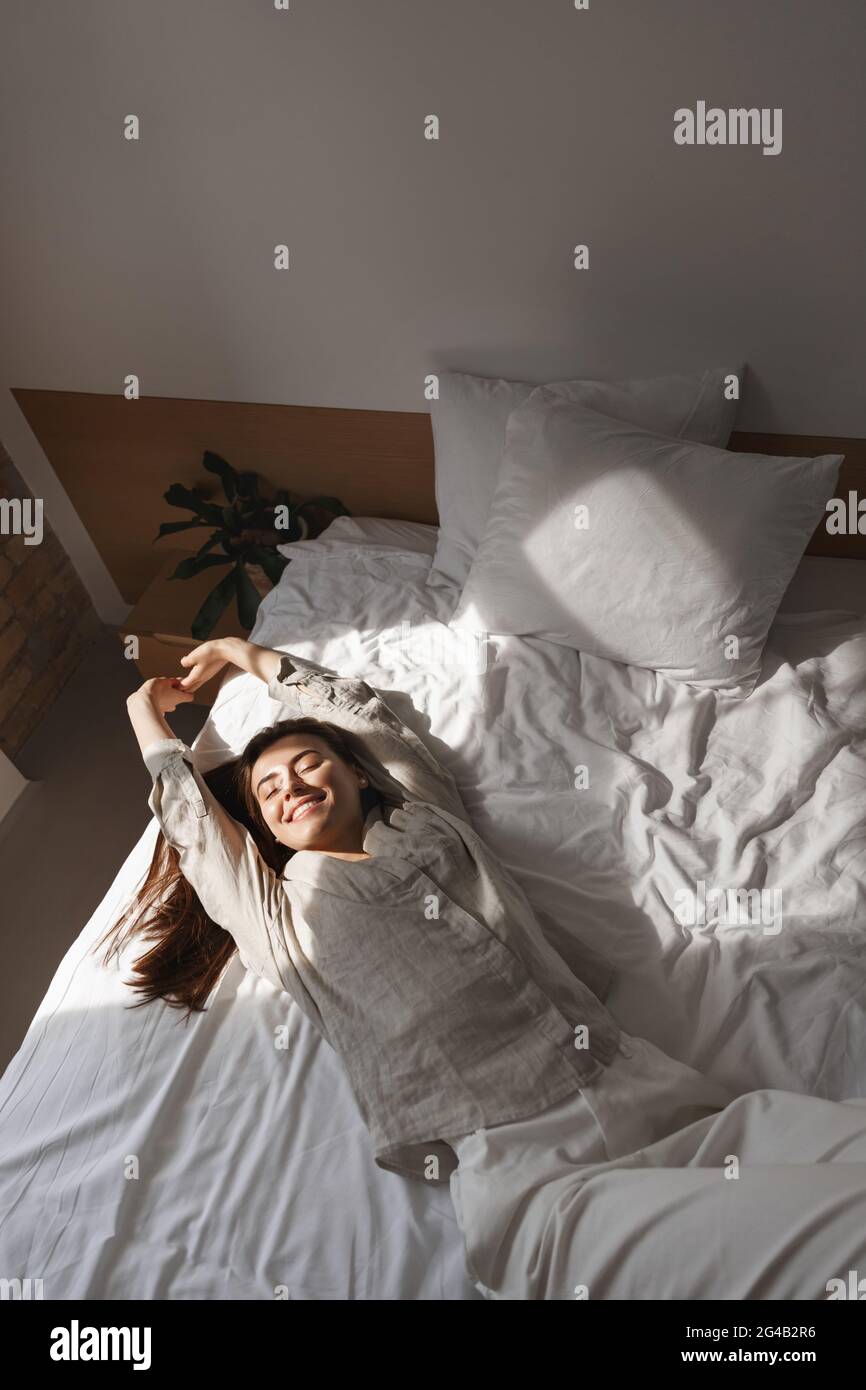 Vertical high angle of young beautiful woman relaxing in her bed ...