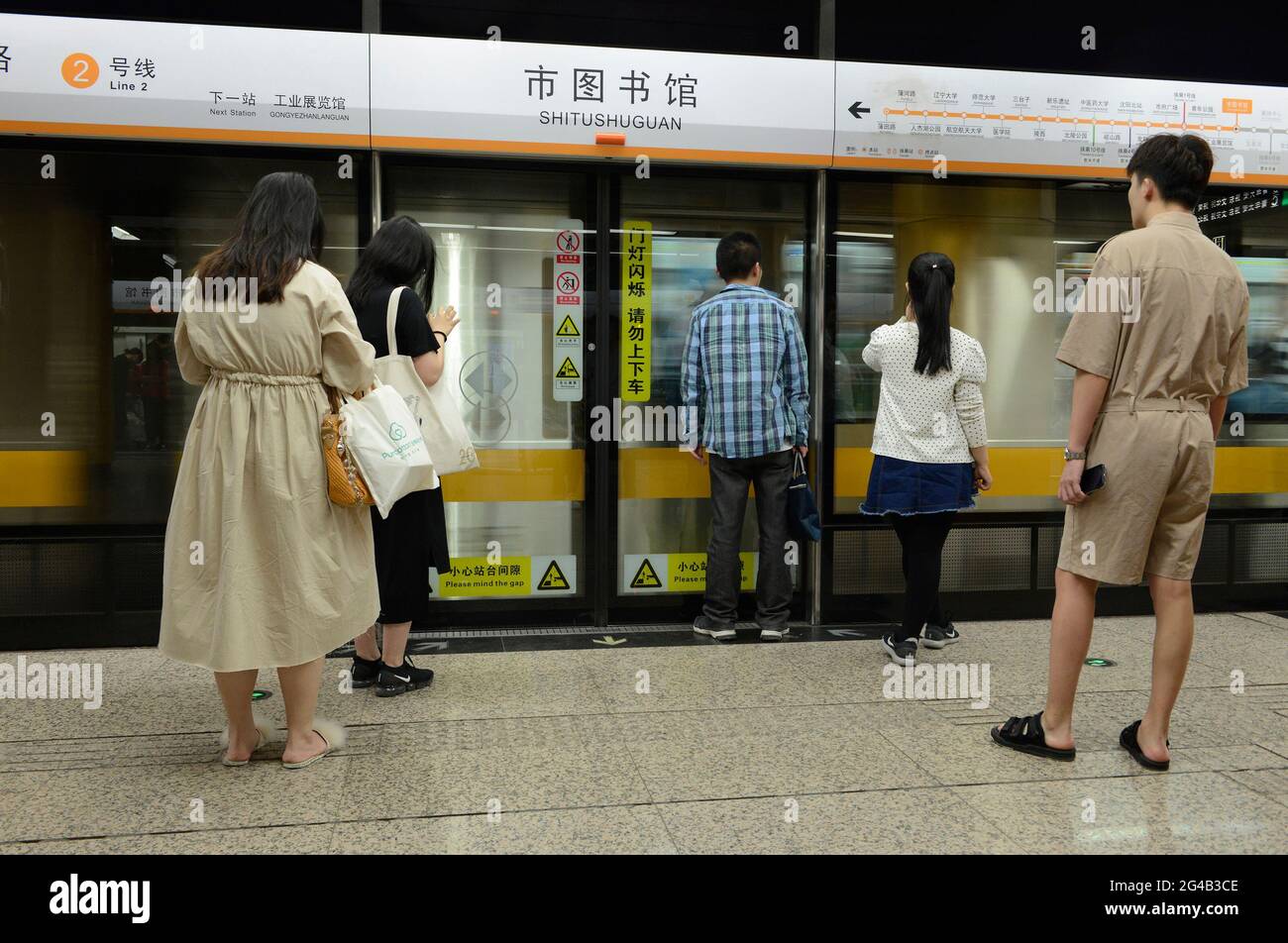 Passengers wait as a train arrives at Tushuguan station on metro line 2 ...