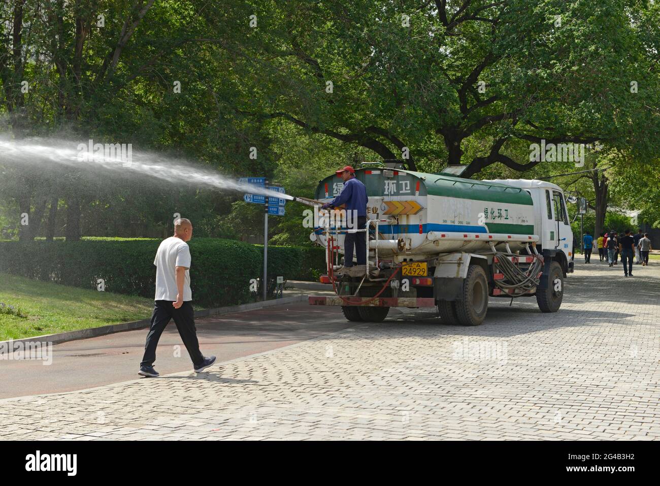 A gardener operates a truck mounted water tank to water the plants in a ...