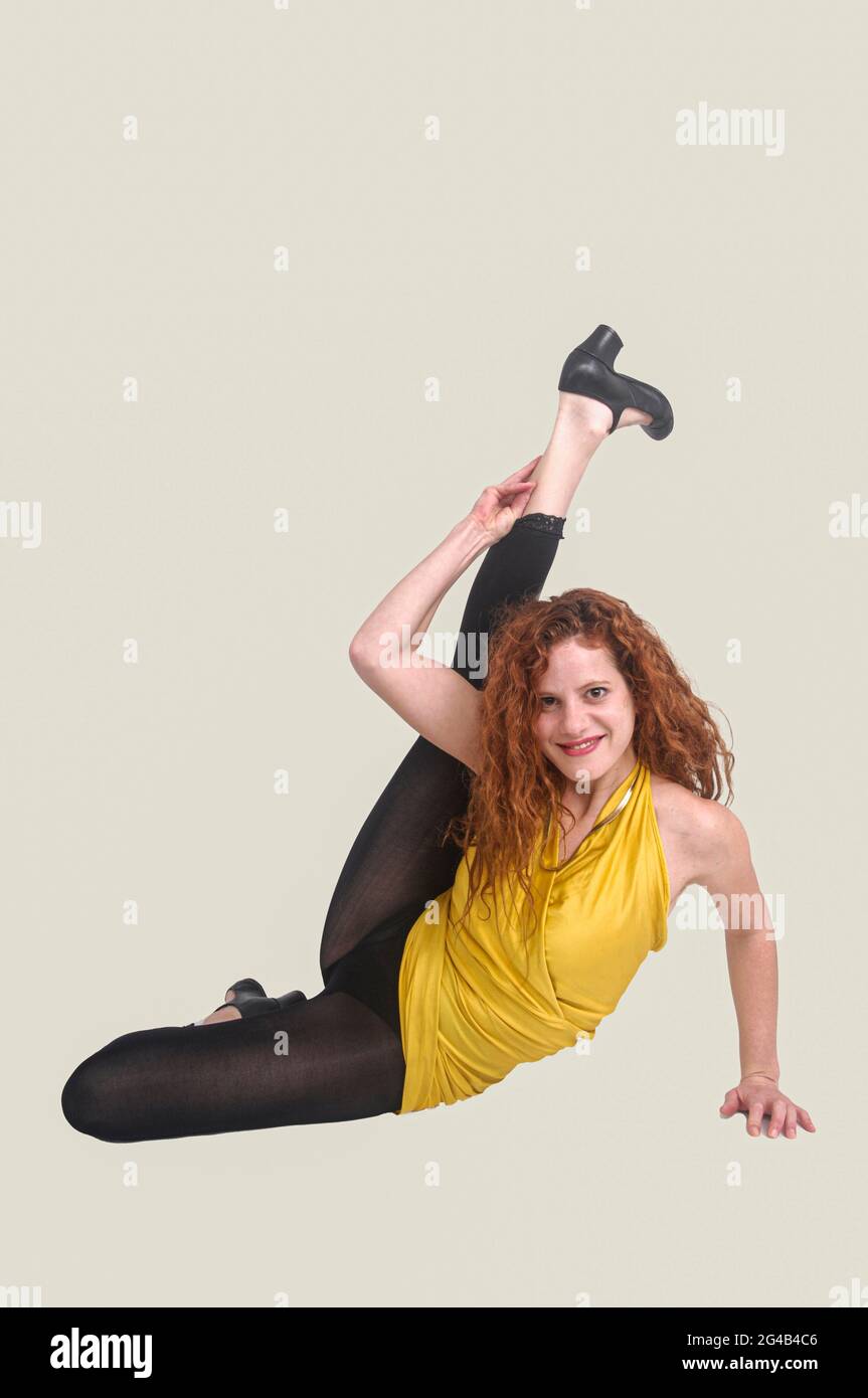 Flexibility concept red haired female model stretching out on white ...