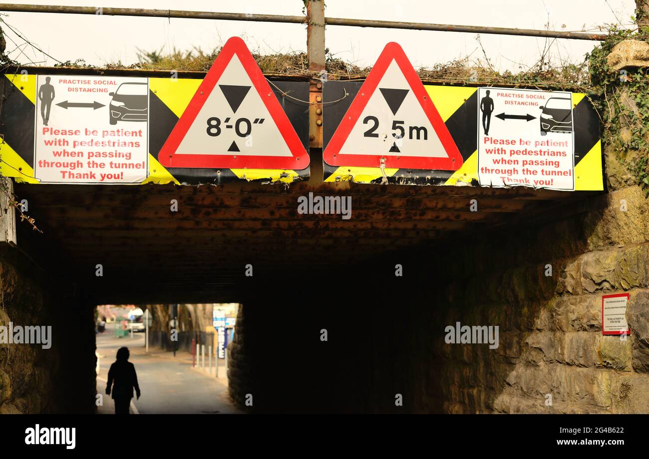 Social distancing signs on a low railway bridge over a narrow tunnel ...
