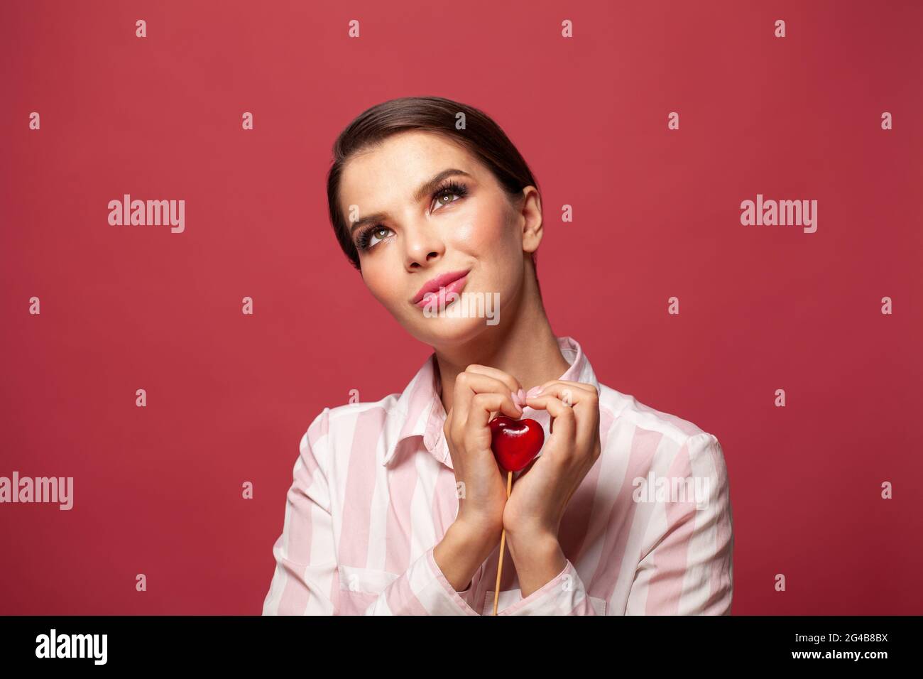 Beautiful happy woman showing love sign on red background Stock Photo ...