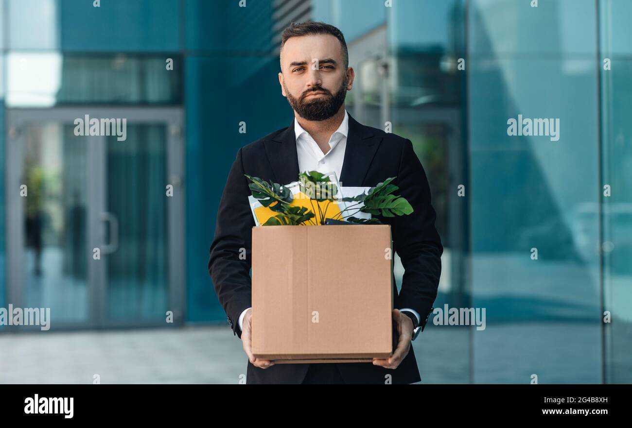 Portrait of fired upset desperate businessman in suit standing outdoors ...