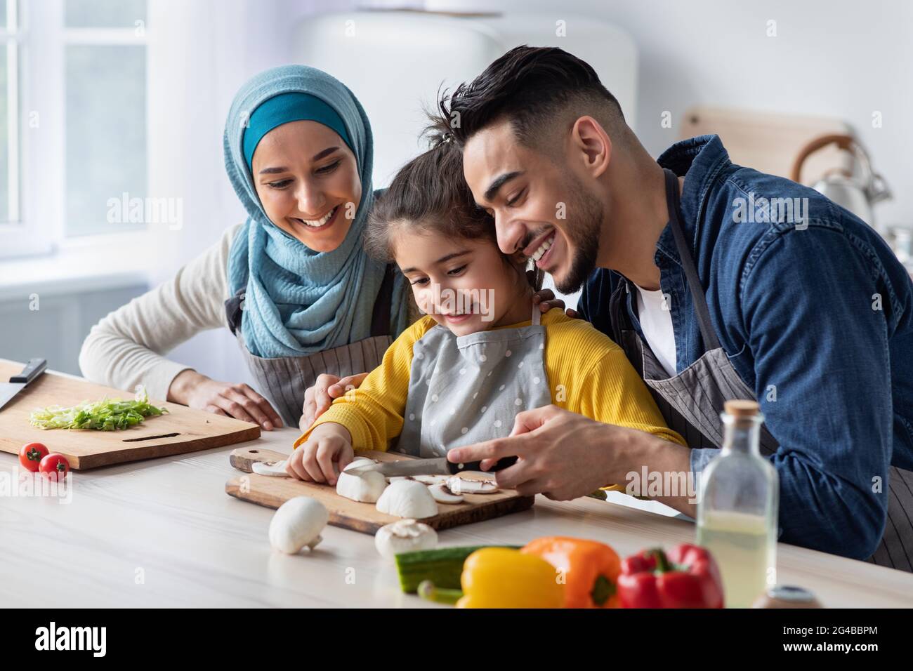 Cheerful middle eastern family of three making healthy dinner together ...