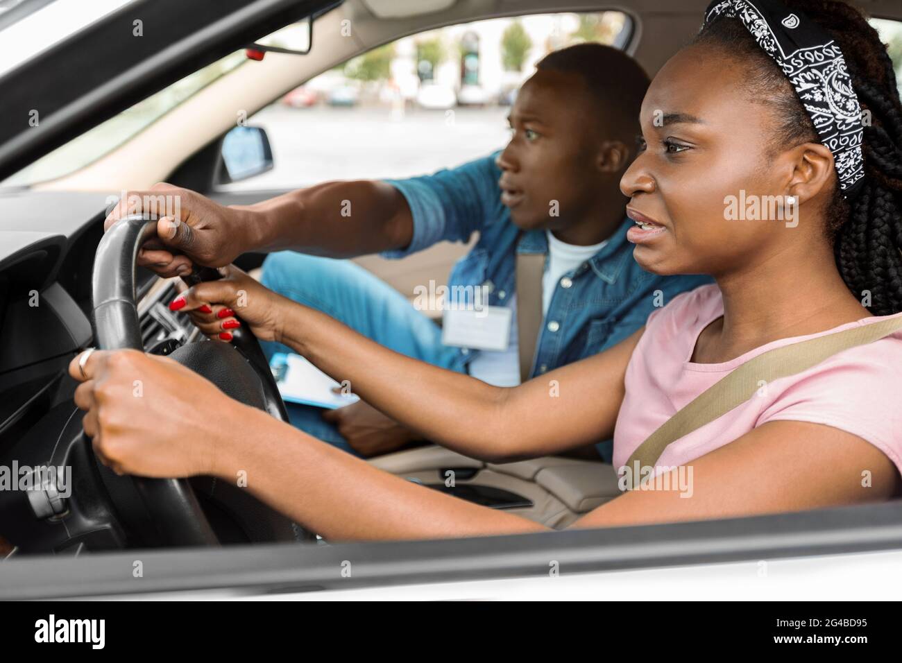 Nervous black lady attending driving school, driving with instructor ...