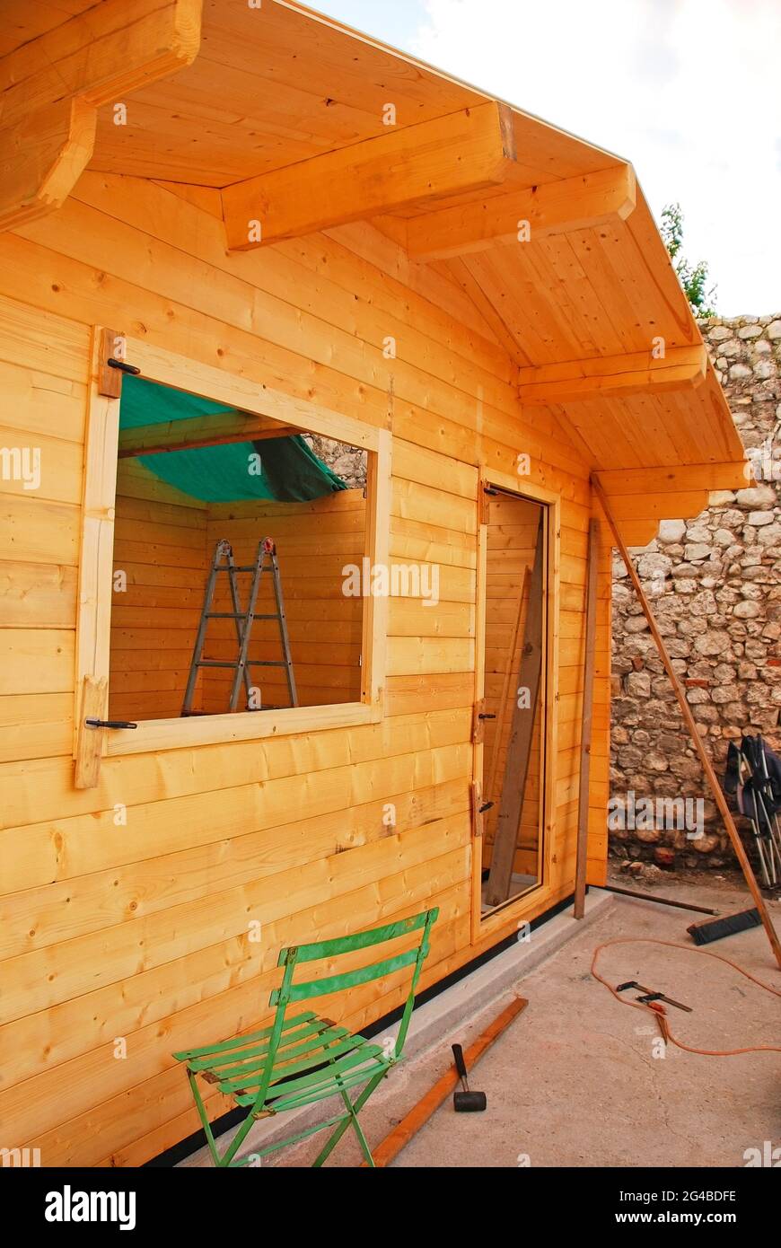 A partially built small prefabricated wooden cabin on a concrete base ...