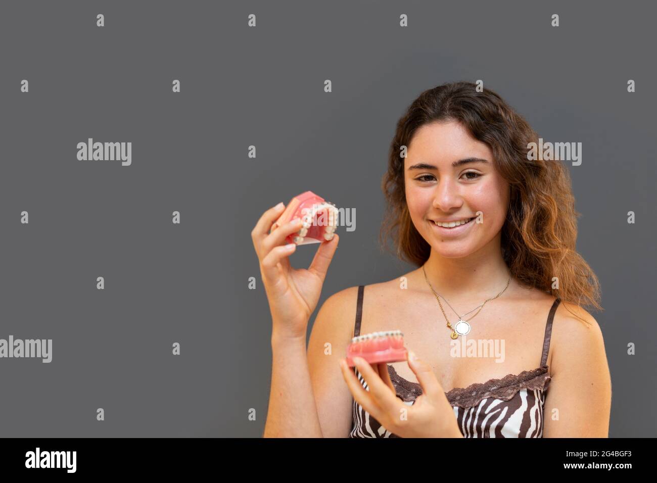 Portrait of smiling girl holding a denture with gray background Stock ...