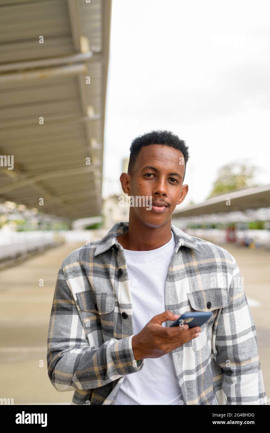 Portrait of African black man outdoors in city during summer vertical ...