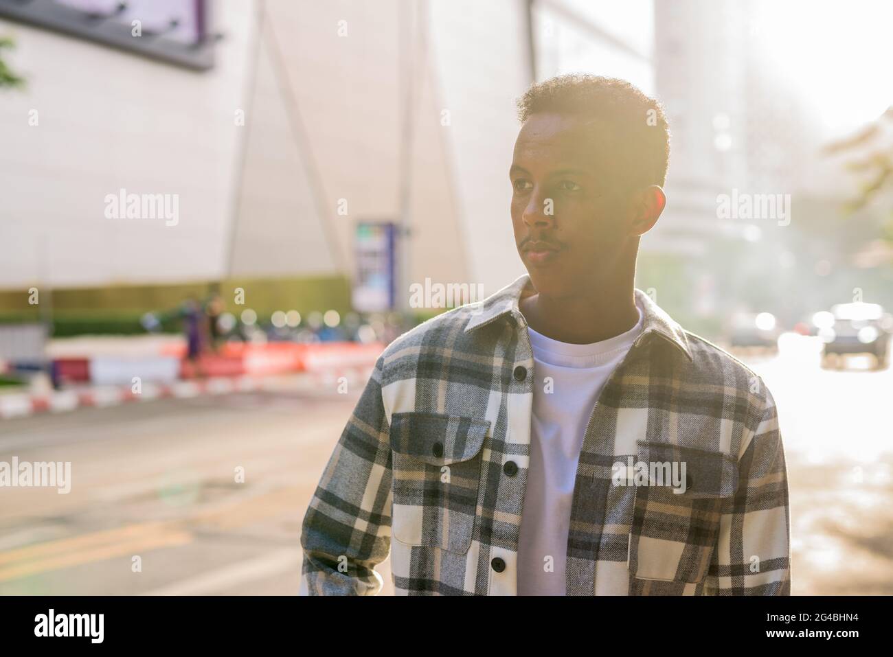 Portrait of African black man outdoors in city during summer back lit ...