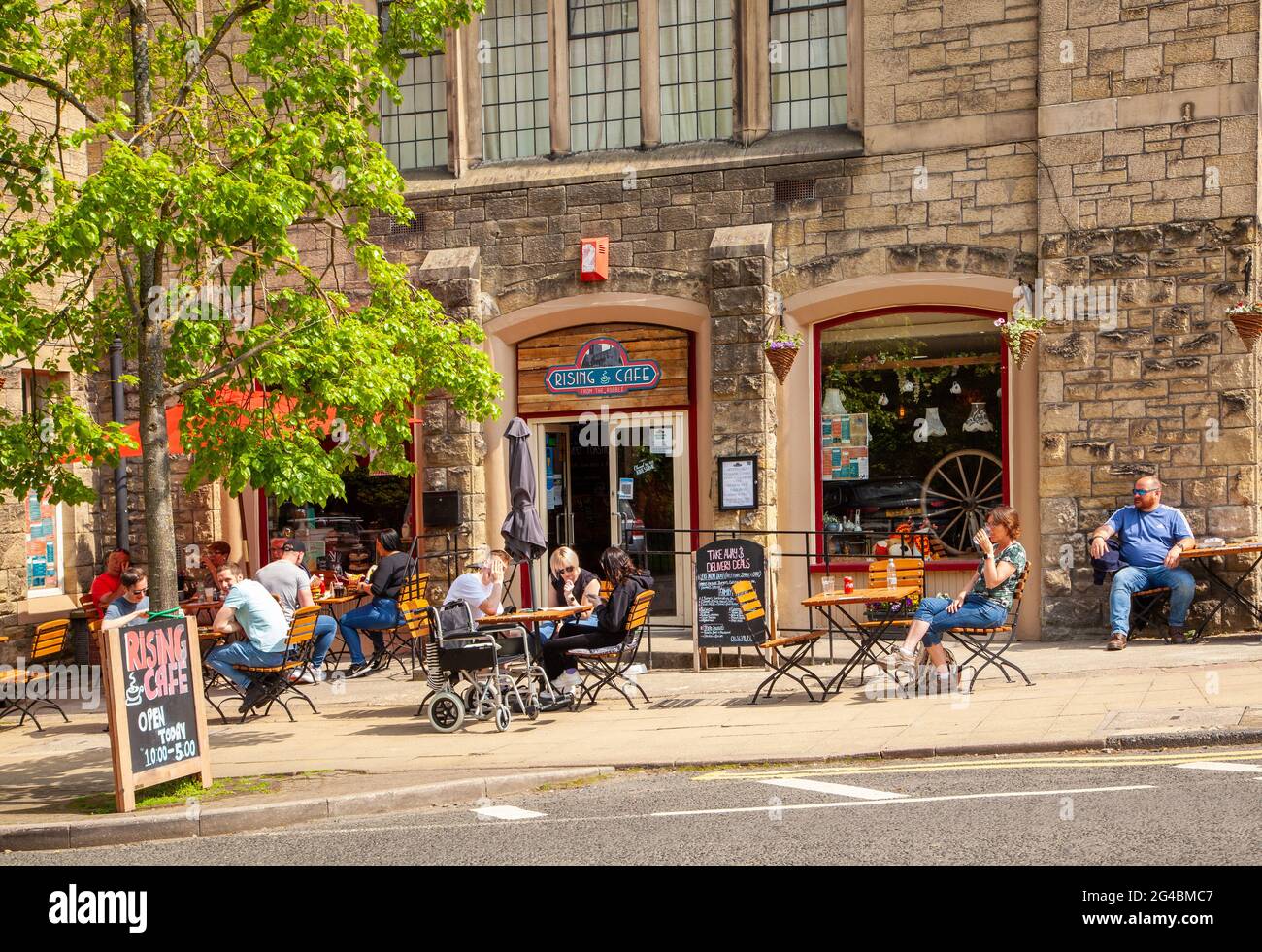 People sitting outside enjoying the sunshine eating and drinking at a ...
