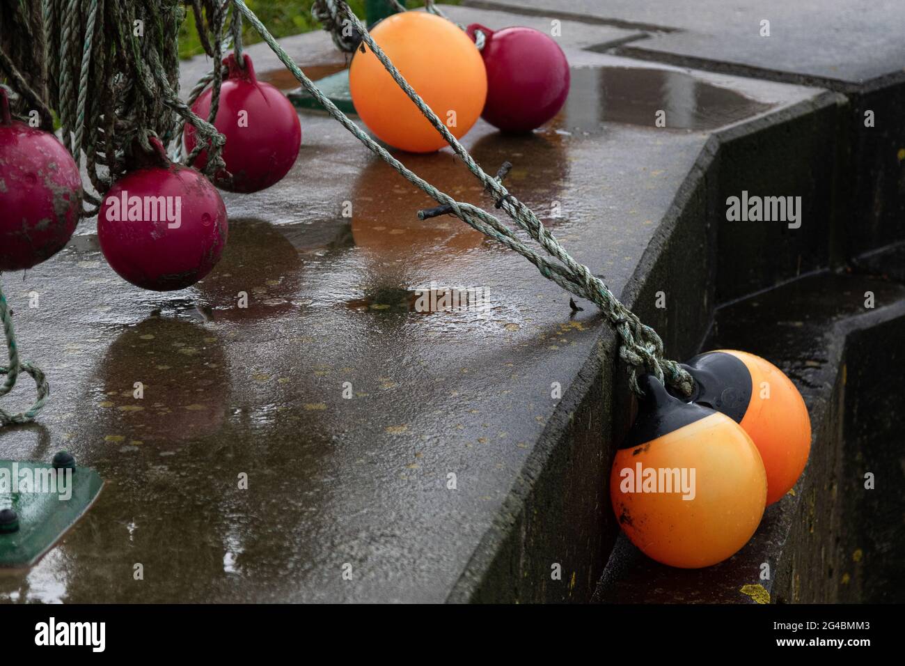 Round marker buoys in orange and dark red and of various sizes hang on ...