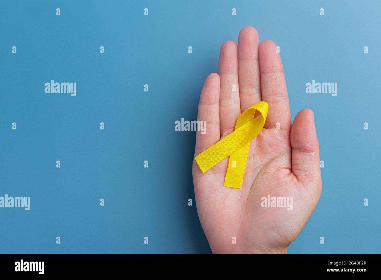 Hands holding yellow ribbon, symbol of cancer awareness, medical ...