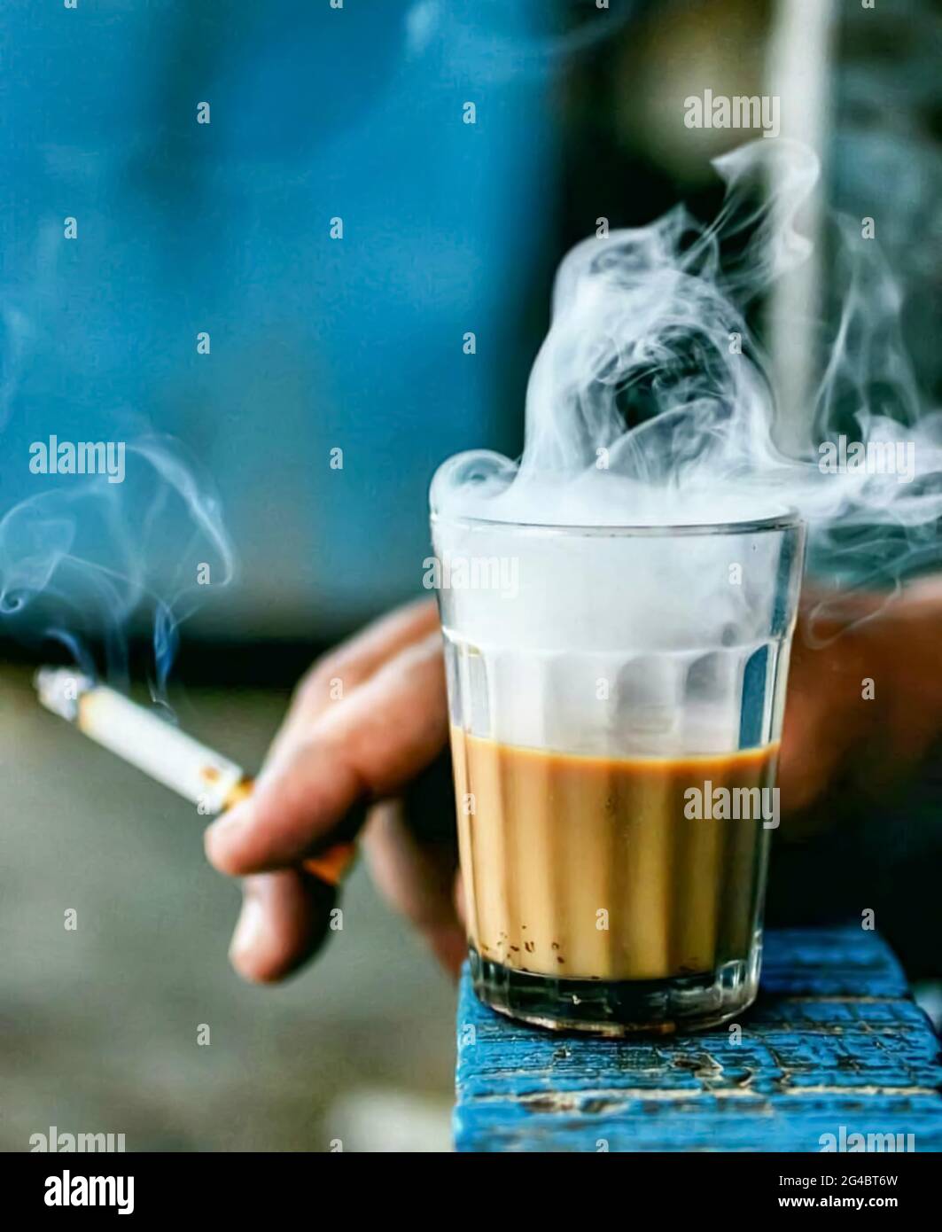 A selective focus of smoking hot coffee in a glass and a blurry hand of ...