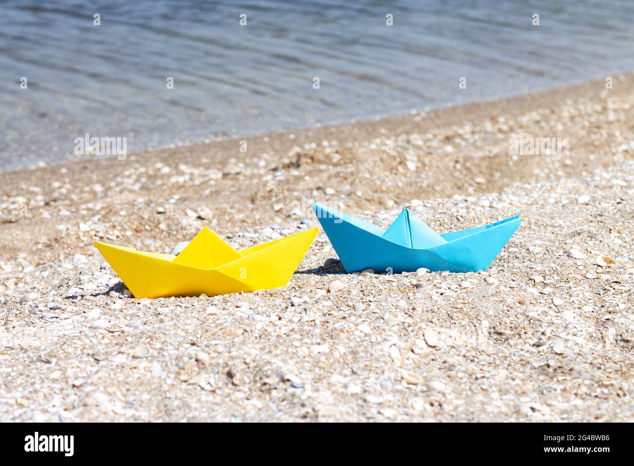 Yellow and blue paper origami boats on the beach Stock Photo - Alamy